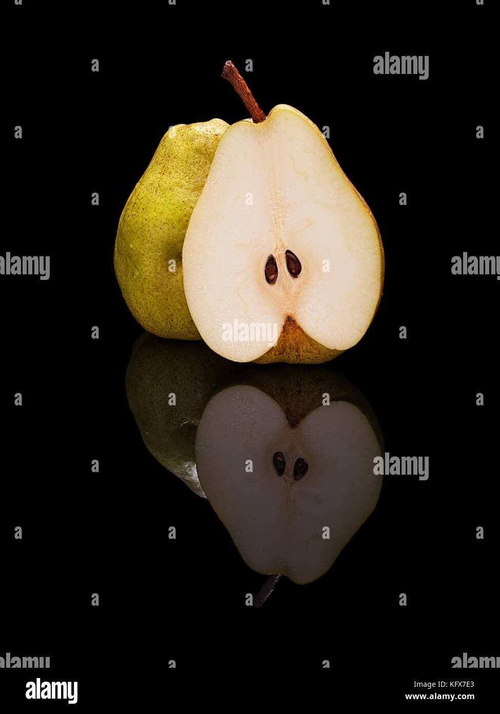 One pear cut in half isolated on black glossy background with real ...