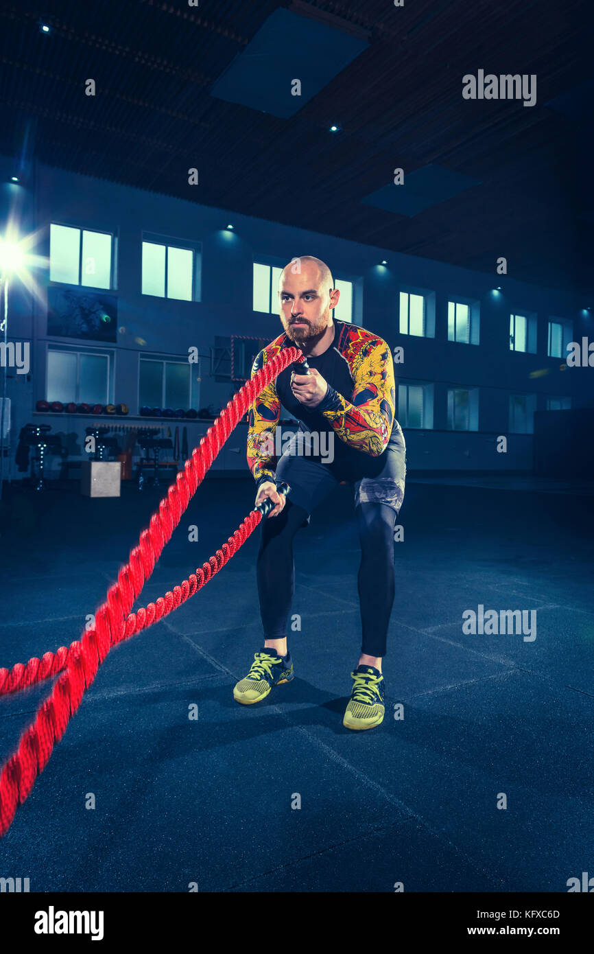 Men with battle rope battle ropes exercise in the fitness gym. CrossFit ...