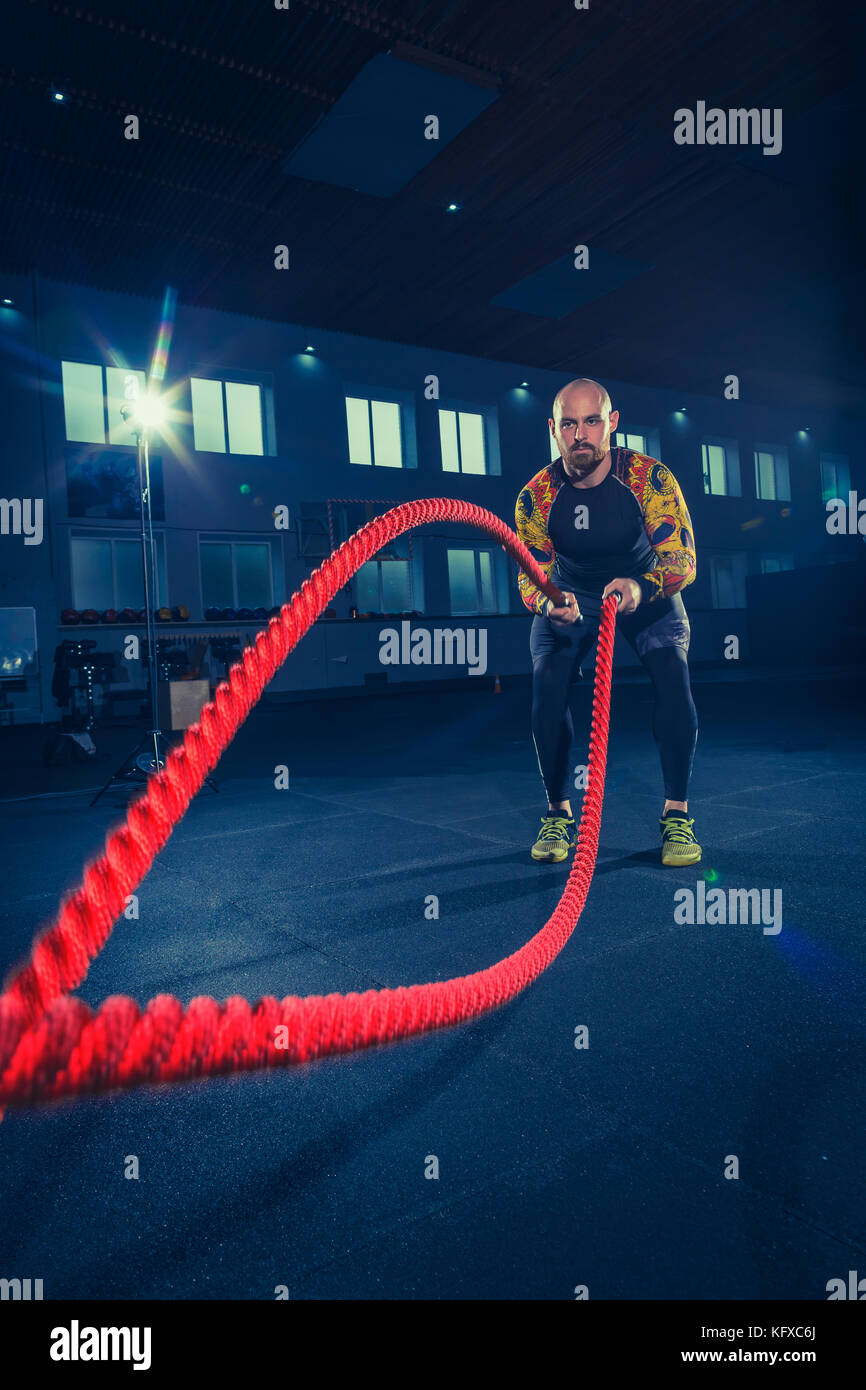 Men with battle rope battle ropes exercise in the fitness gym. CrossFit ...