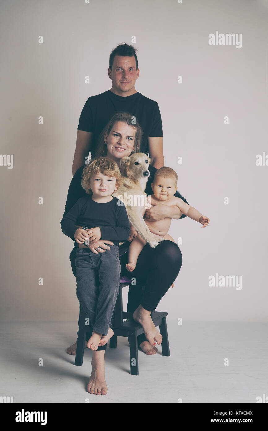 Two generation family studio portrait with dog on grey and white ...