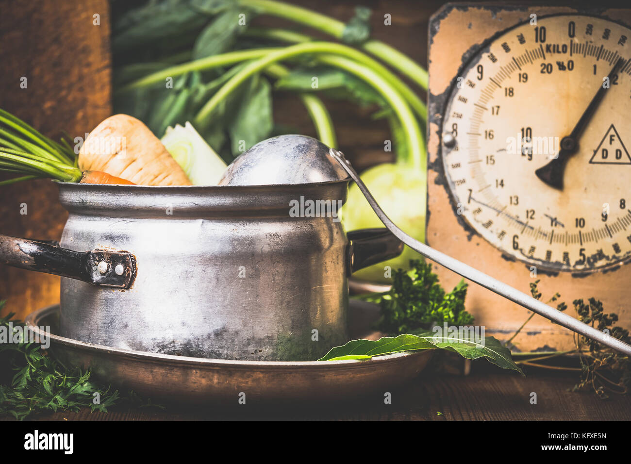 Old cooking pot with raw vegetables and ladle on rustic kitchen table ...