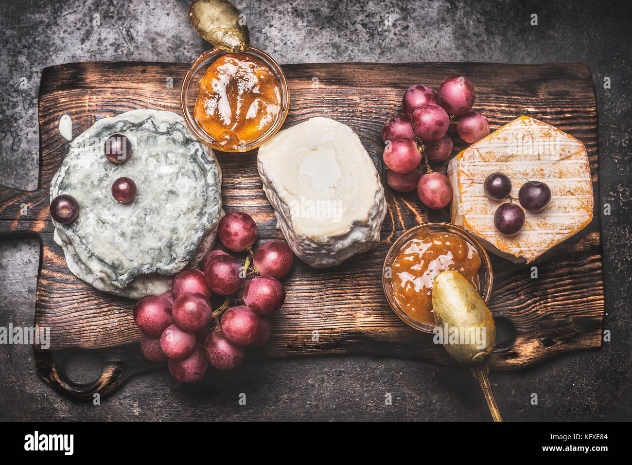 Rustic cheese plate with various cheese, grape and honey mustard sauces ...