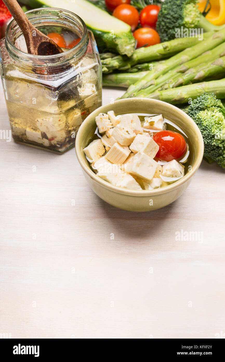 Pickled Diced feta cheese in olives oil and vegetables on white wooden ...