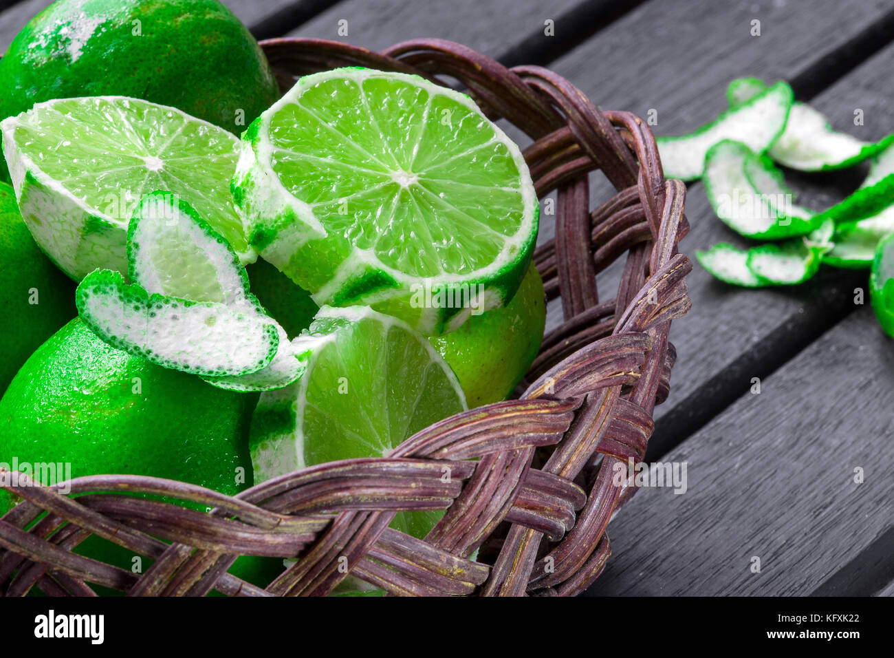 Fresh and colorful green lemons and lime on a wooden vine basket, cut ...