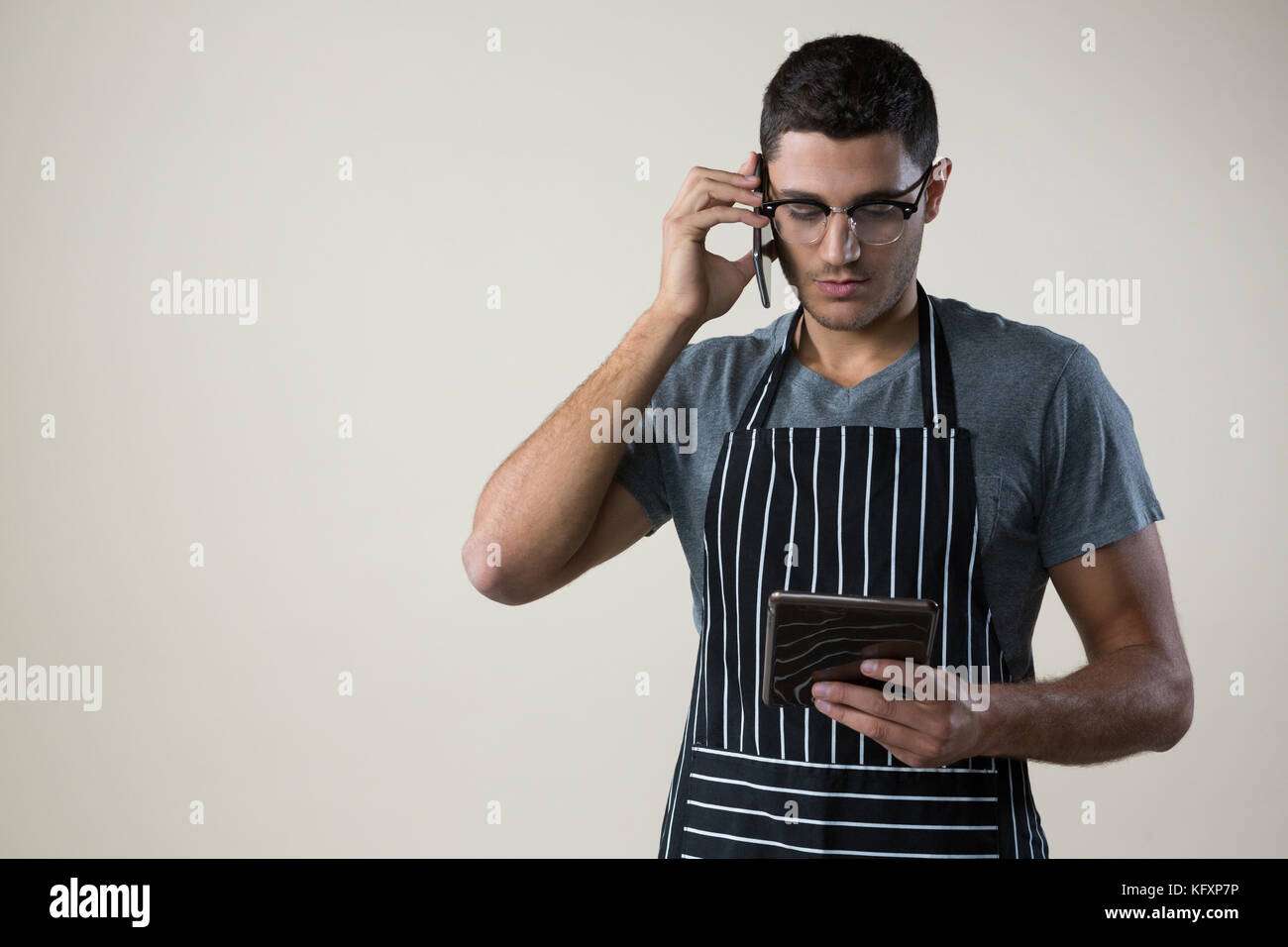 Close-up of waiter looking at the digital tablet while talking on the ...
