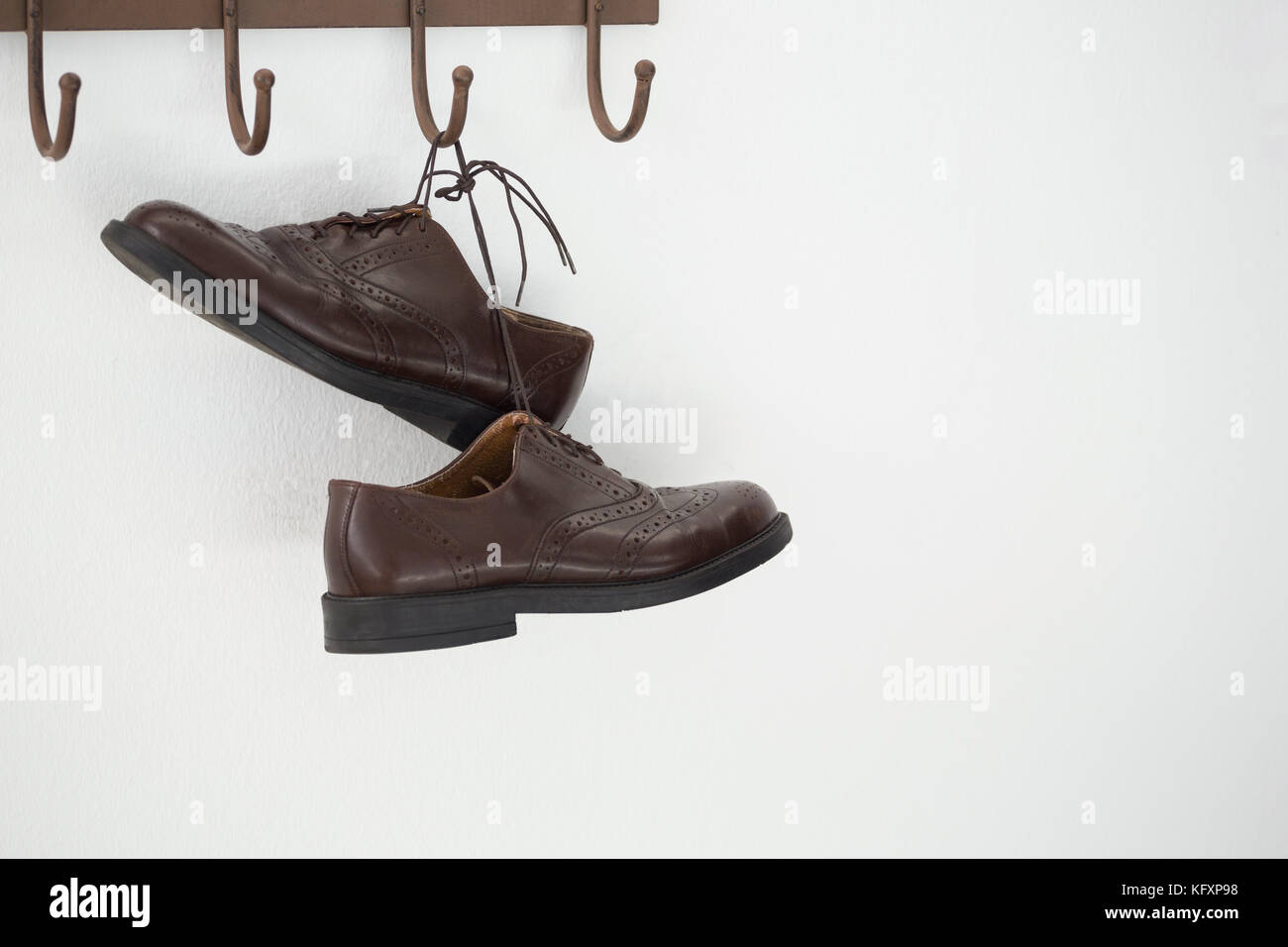Pair of shoes hanging on hook against white wall Stock Photo - Alamy