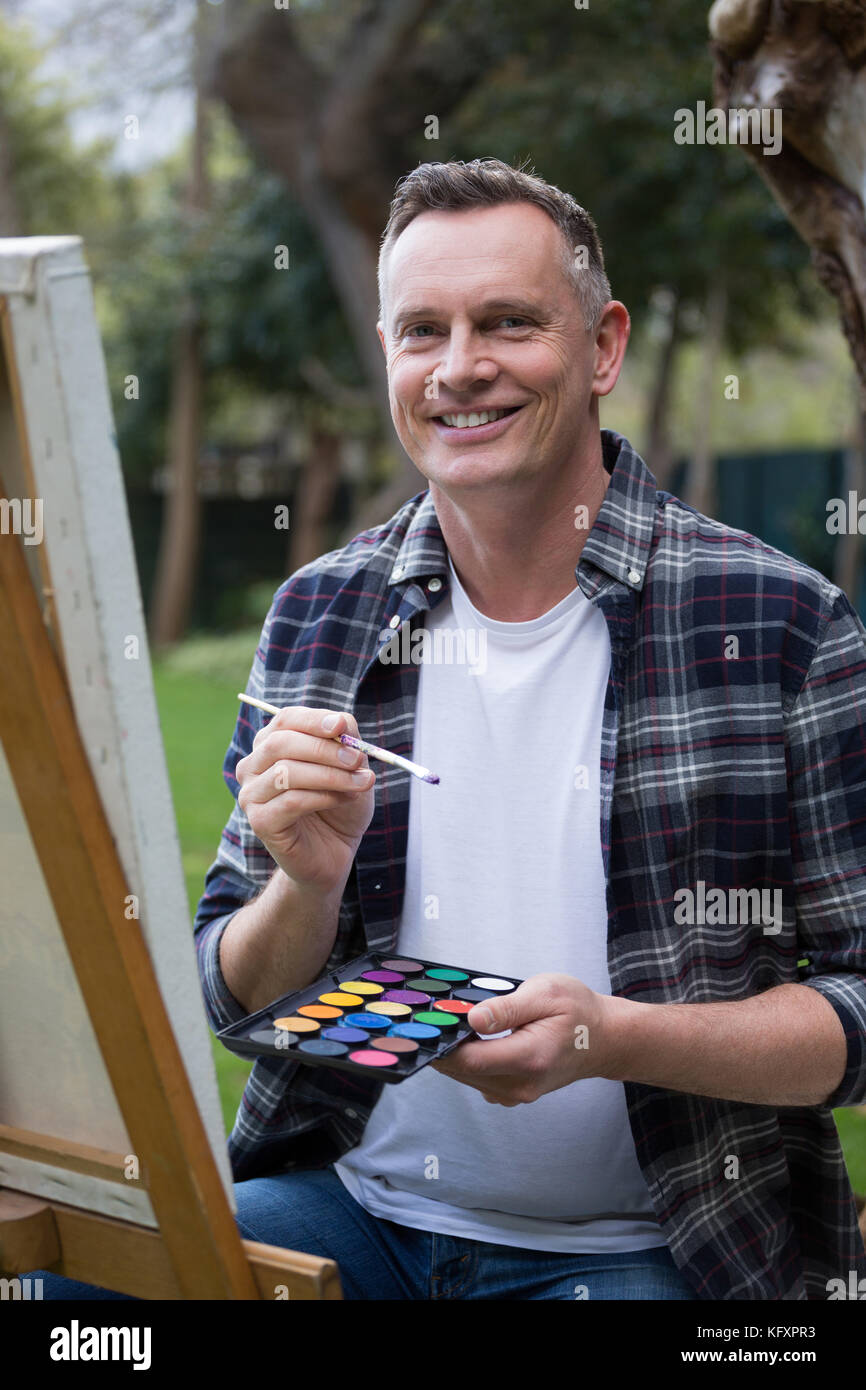 Smiling man painting on canvas in garden Stock Photo - Alamy