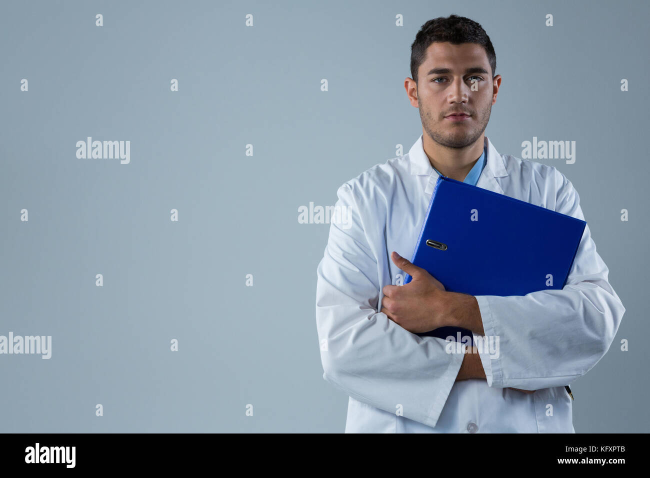 Doctor standing with a file against white background Stock Photo - Alamy