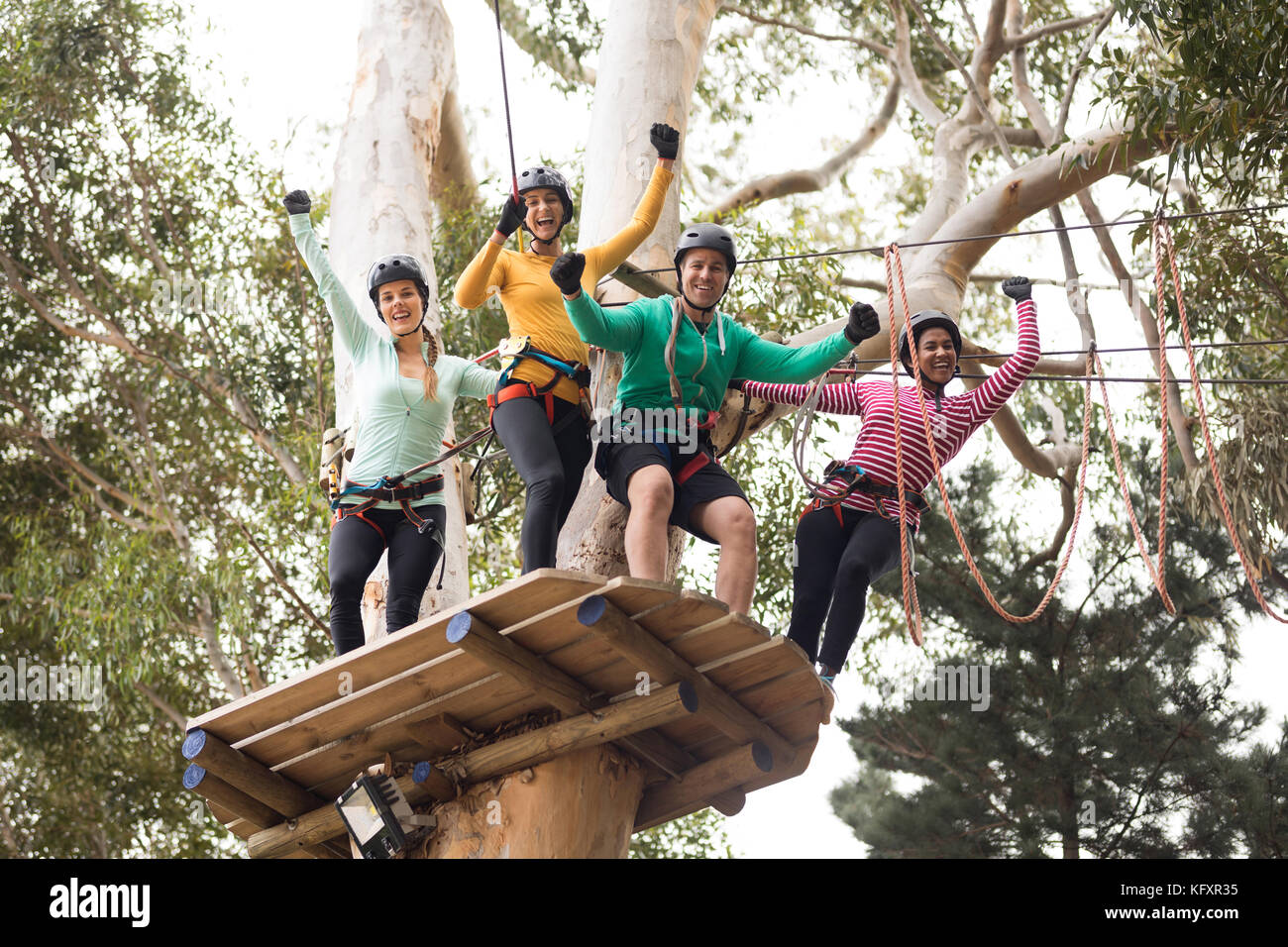 Friends enjoying zip line adventure in park on a sunny day Stock Photo ...