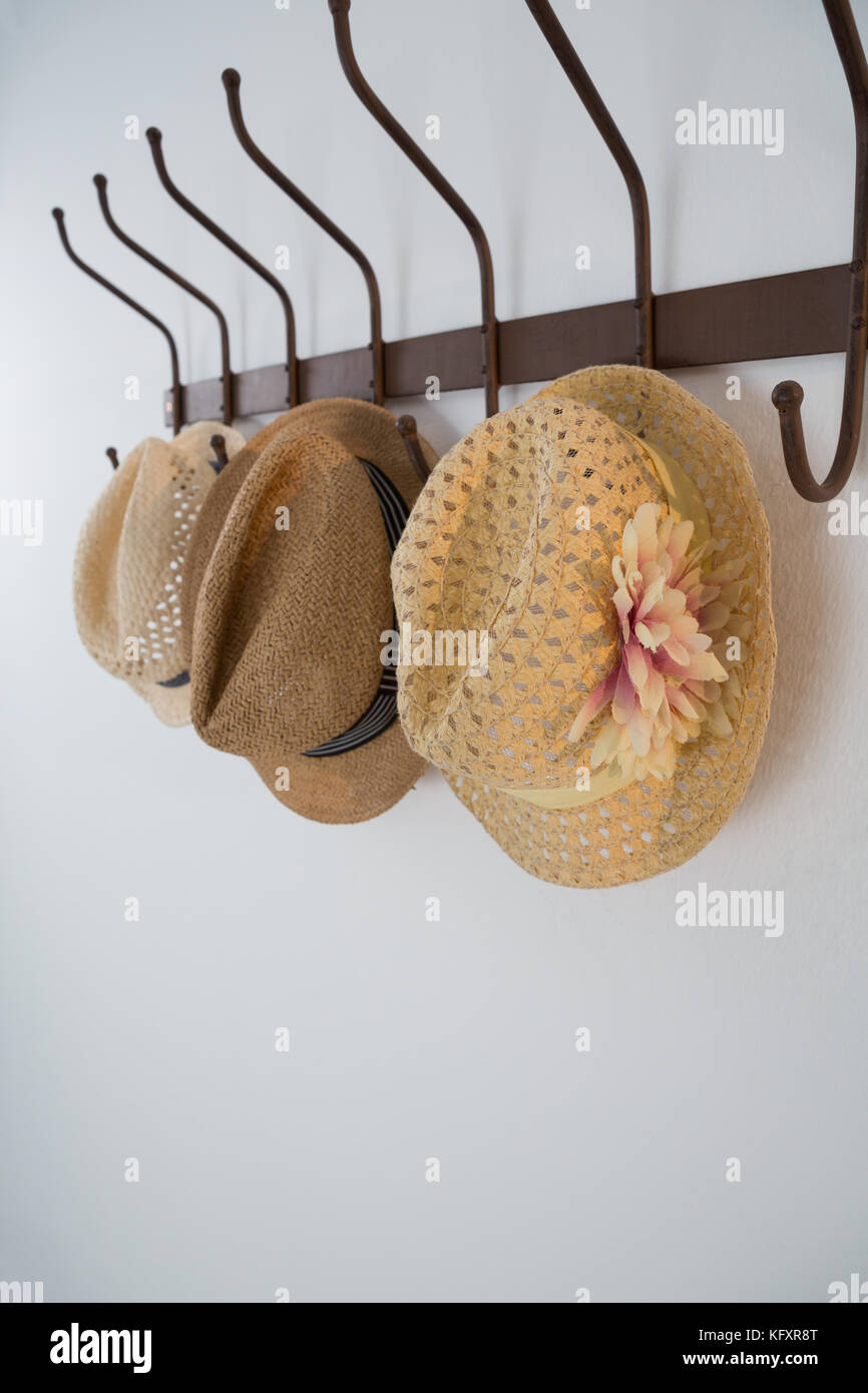Hats hanging on hook against white wall Stock Photo - Alamy