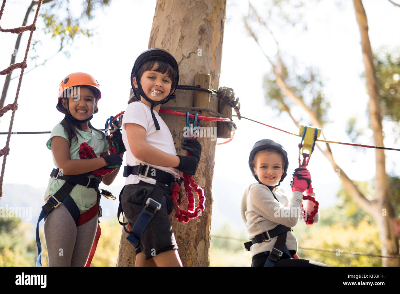 Happy kids enjoying zip line adventure on sunny day Stock Photo - Alamy