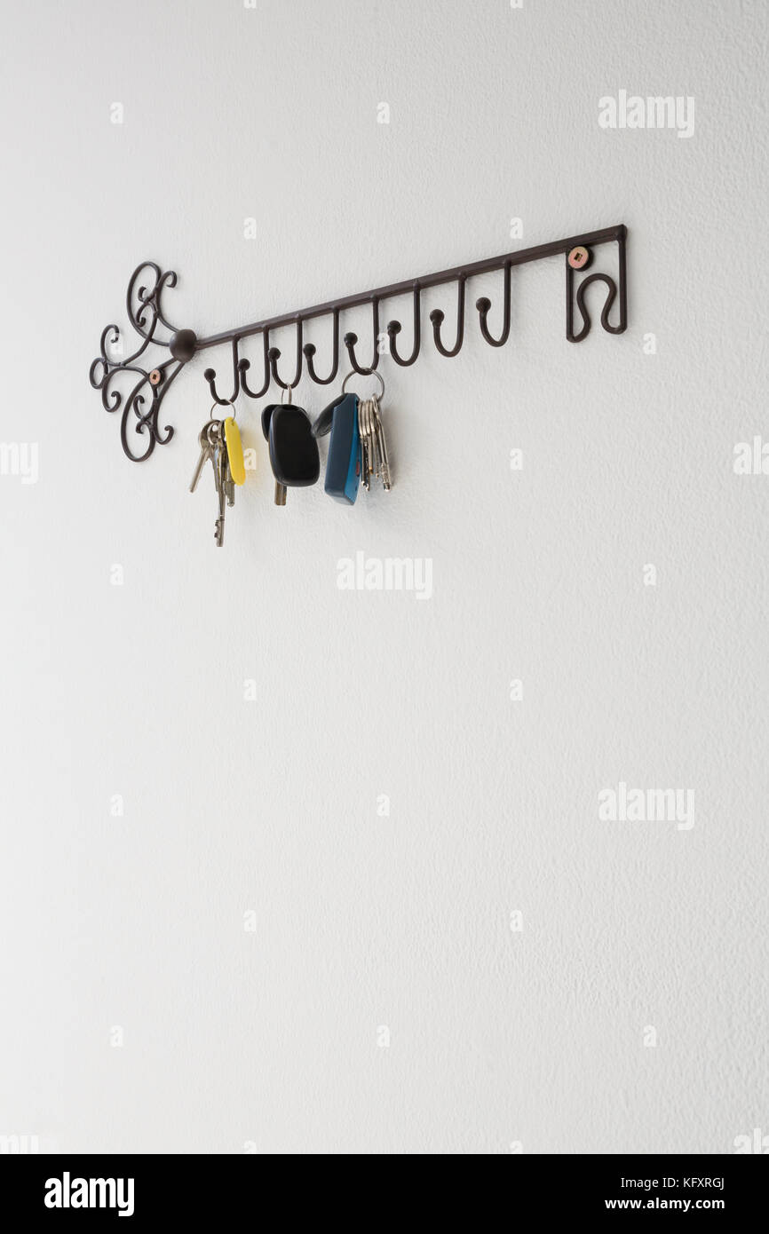 Various keys hanging on hook against white wall Stock Photo - Alamy