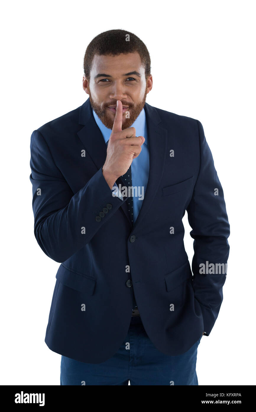 Businessman standing with finger on lips against white background Stock ...