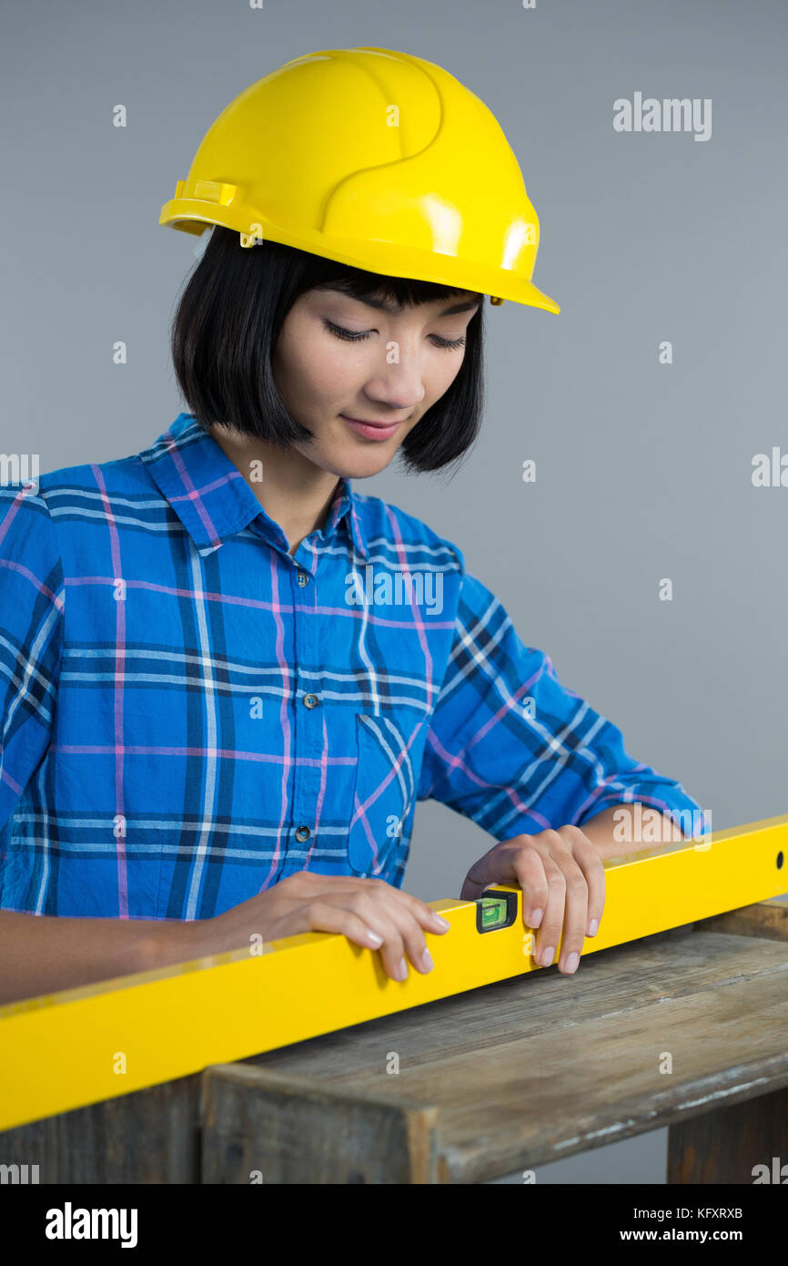Female architect measuring plywood with engineer scale against grey ...