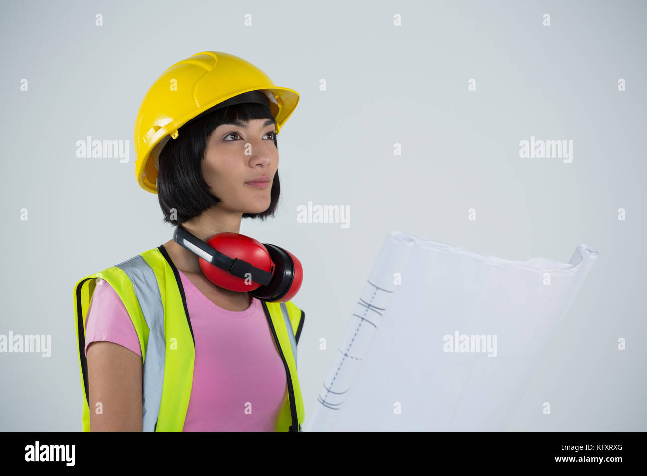 Thoughtful female architect holding blueprint against white background ... Thoughtful female architect holding blueprint against white background ...