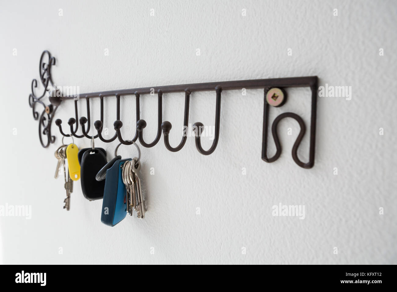 Close-up of various keys hanging on hook against white wall Stock Photo ...