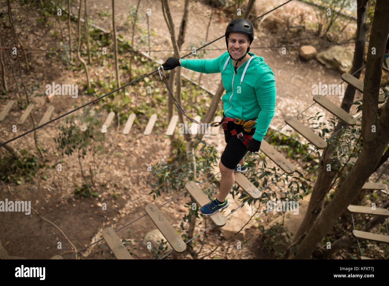 Portrait of happy man walking on rope bridge in adventure park Stock ...