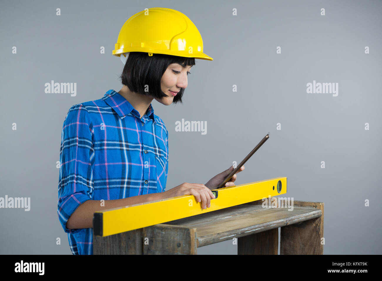 Female architect measuring plywood with engineer scale against grey ...