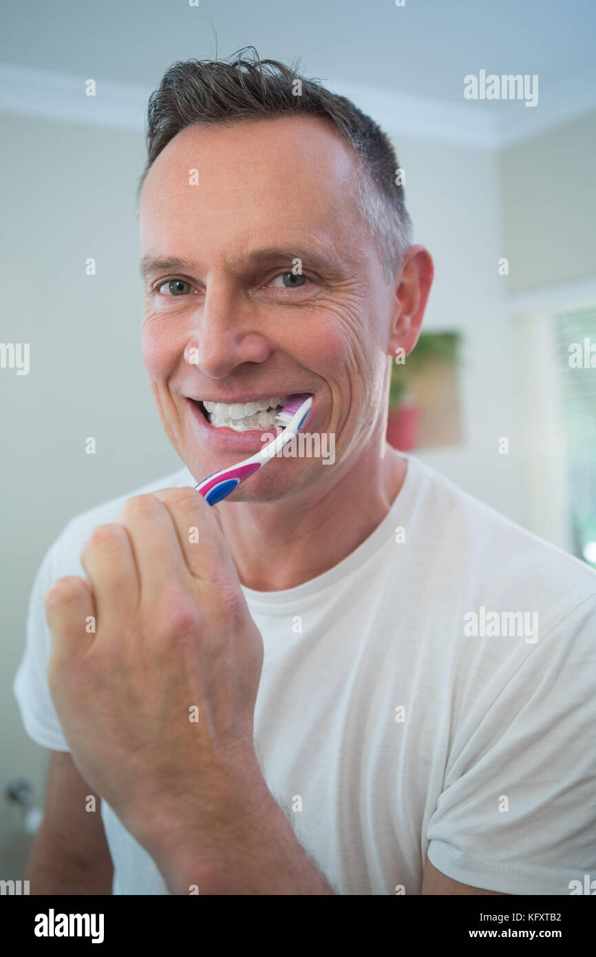 Portrait of man brushing his teeth with toothbrush in bathroom Stock ...