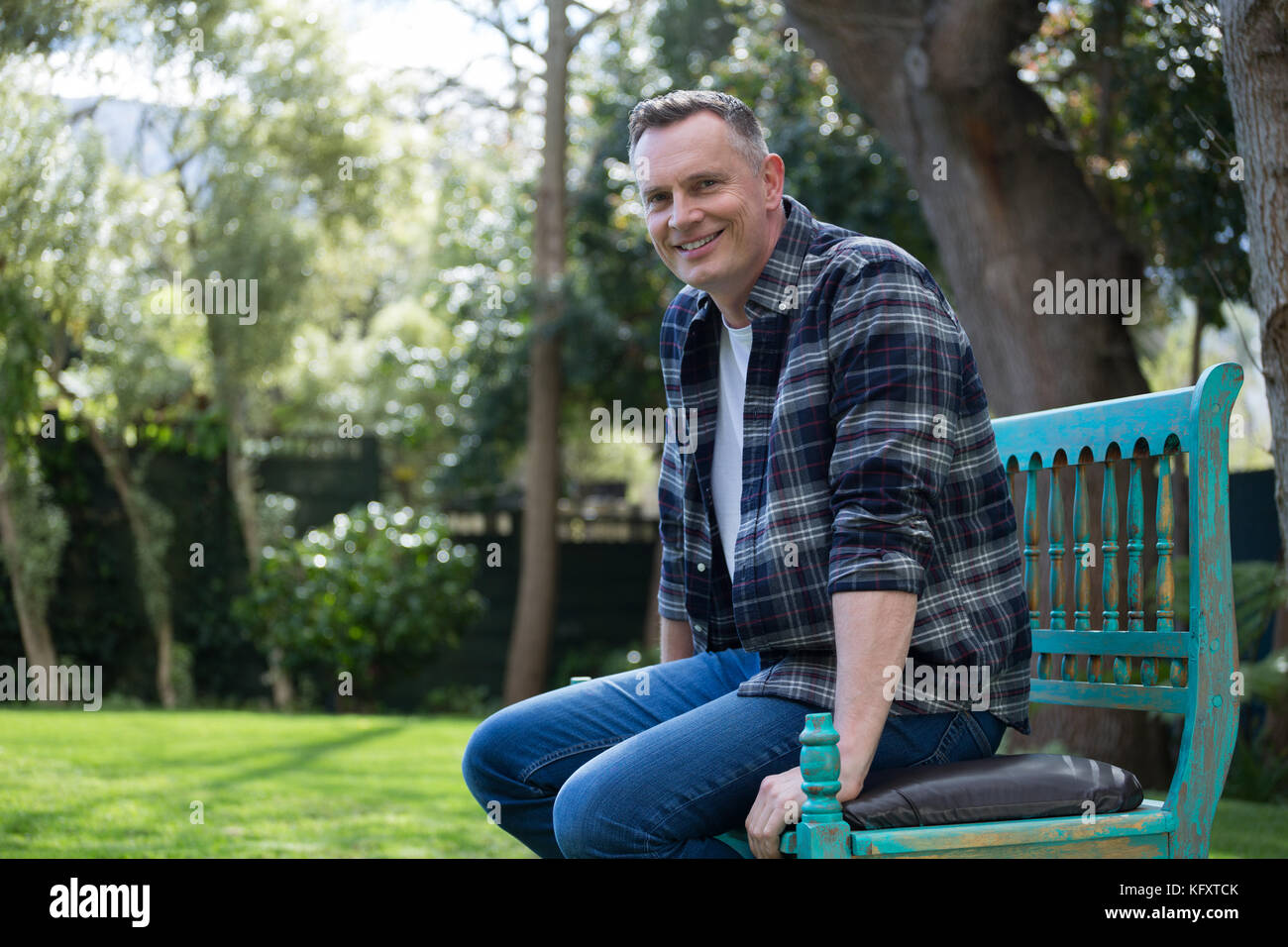 Portrait of smiling man sitting on bench in garden Stock Photo - Alamy