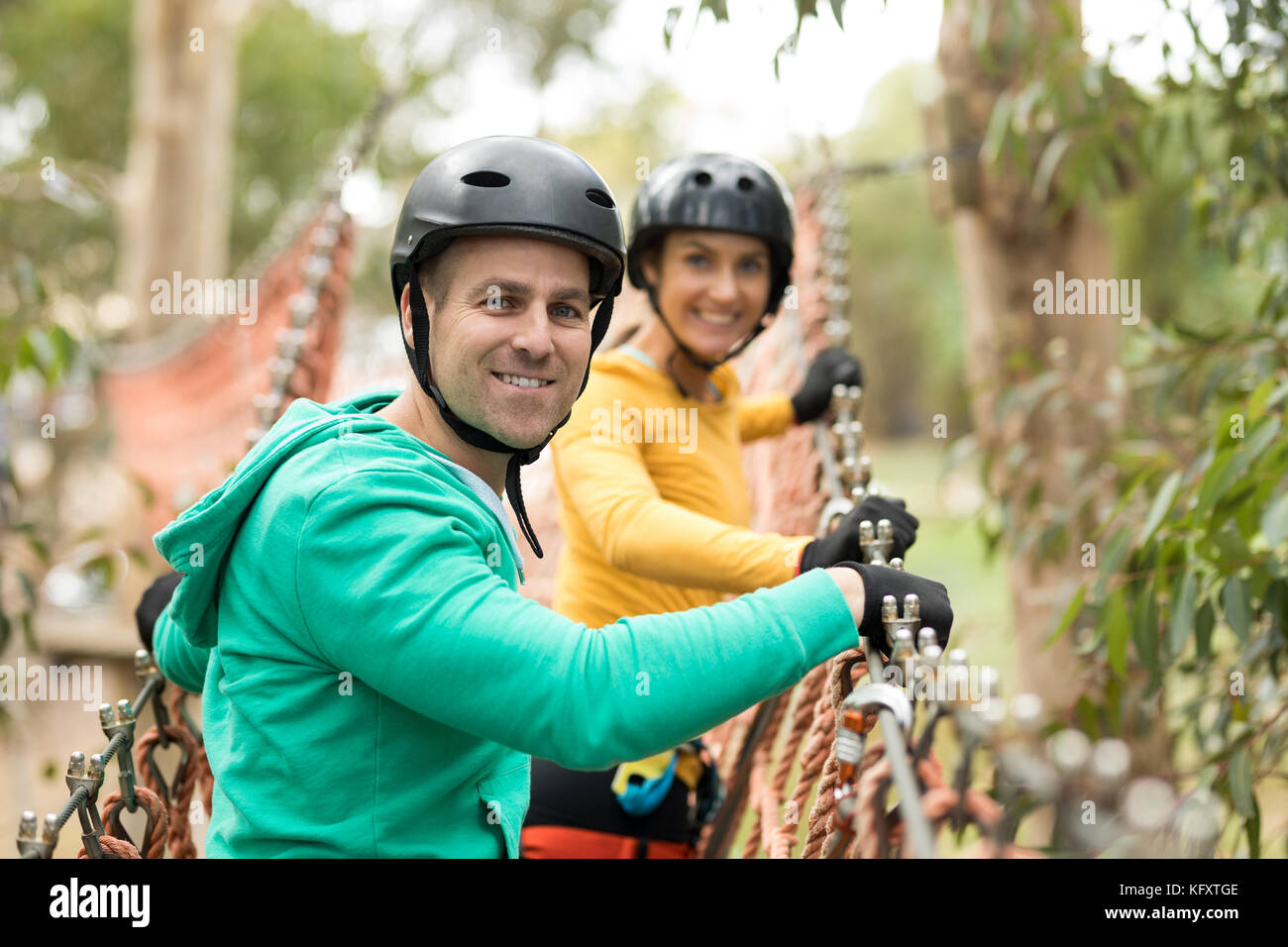 Happy couple standing on rope bridge Stock Photo - Alamy