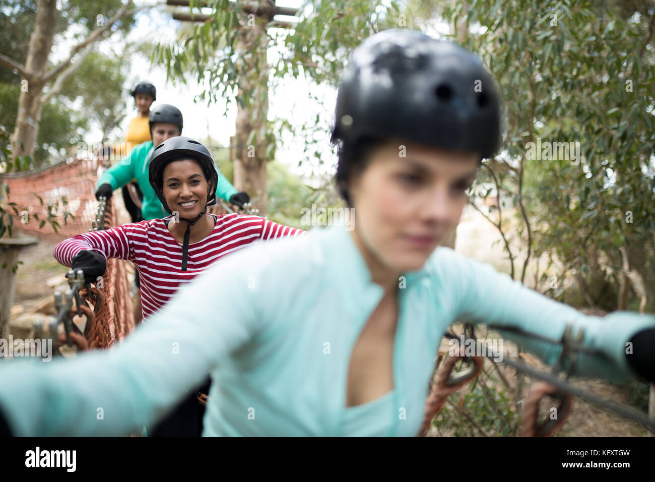 Smiling friends walking on rope bridge Stock Photo - Alamy