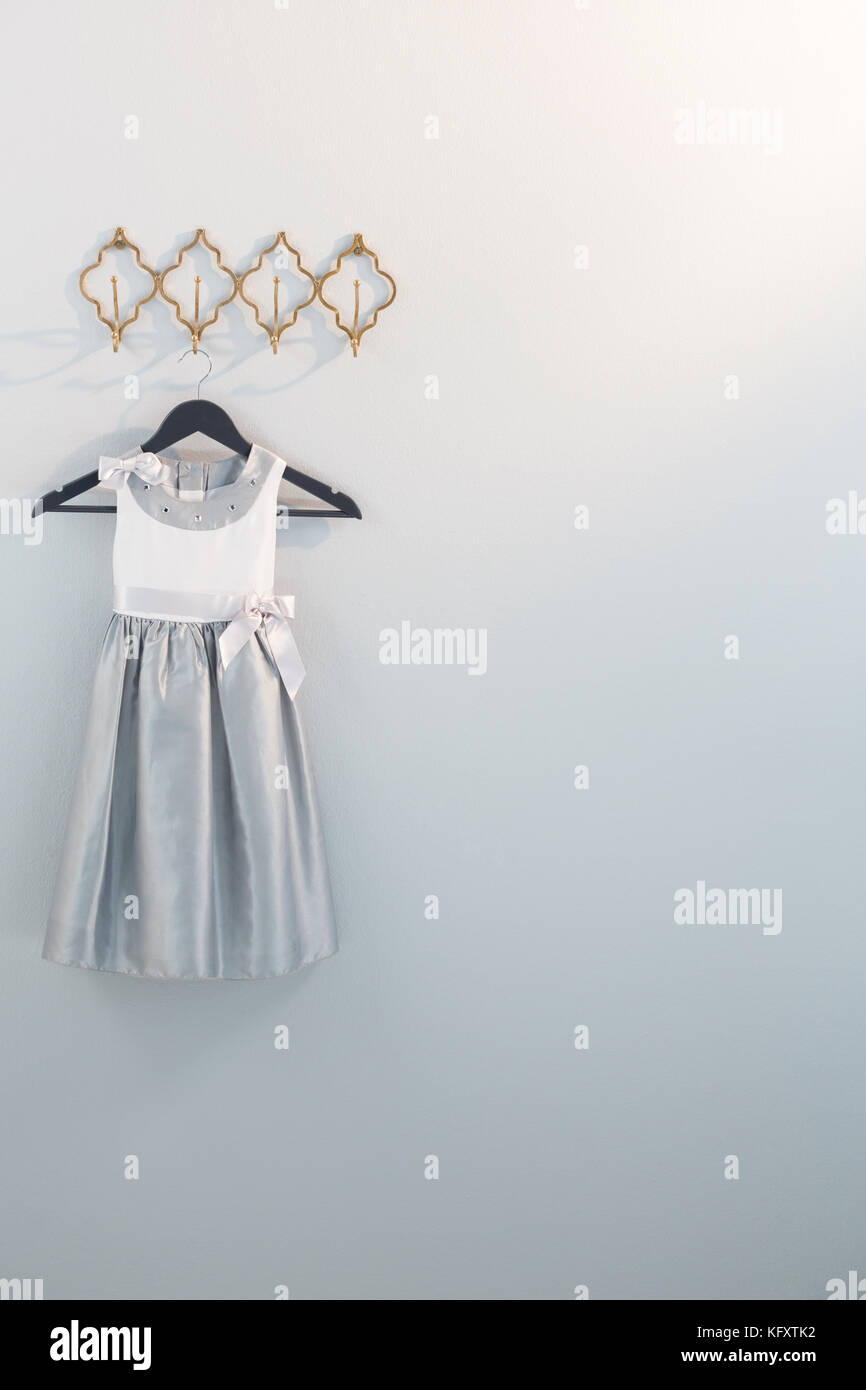 Dress hanging on hook against white wall Stock Photo - Alamy