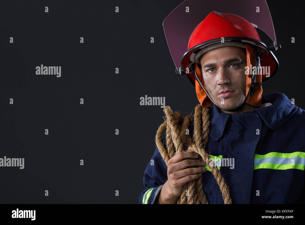 Portrait of fireman standing with a rope Stock Photo - Alamy