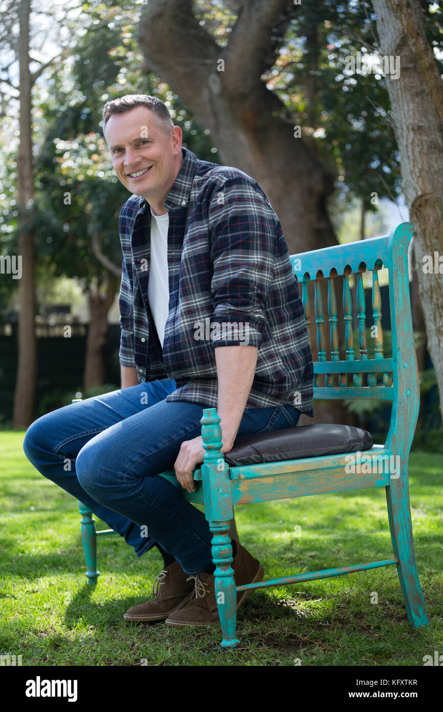 Portrait of smiling man sitting on bench in garden Stock Photo - Alamy