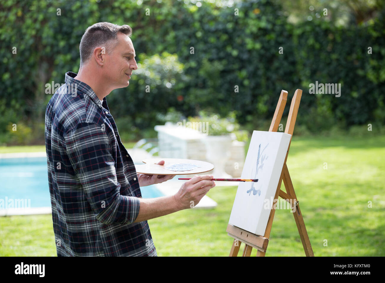 Smiling man painting on canvas in garden Stock Photo - Alamy