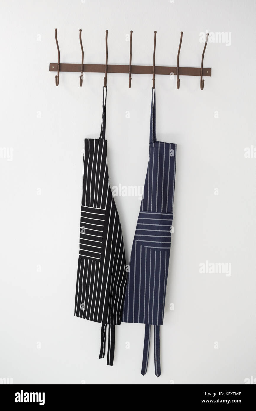 Apron hanging on hook against white wall Stock Photo - Alamy