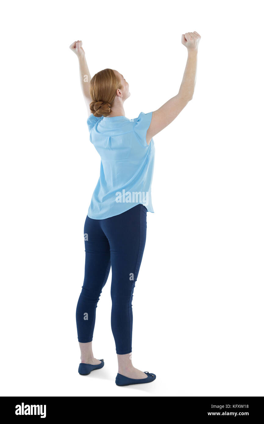 Young female executive standing with arms up against white background ...