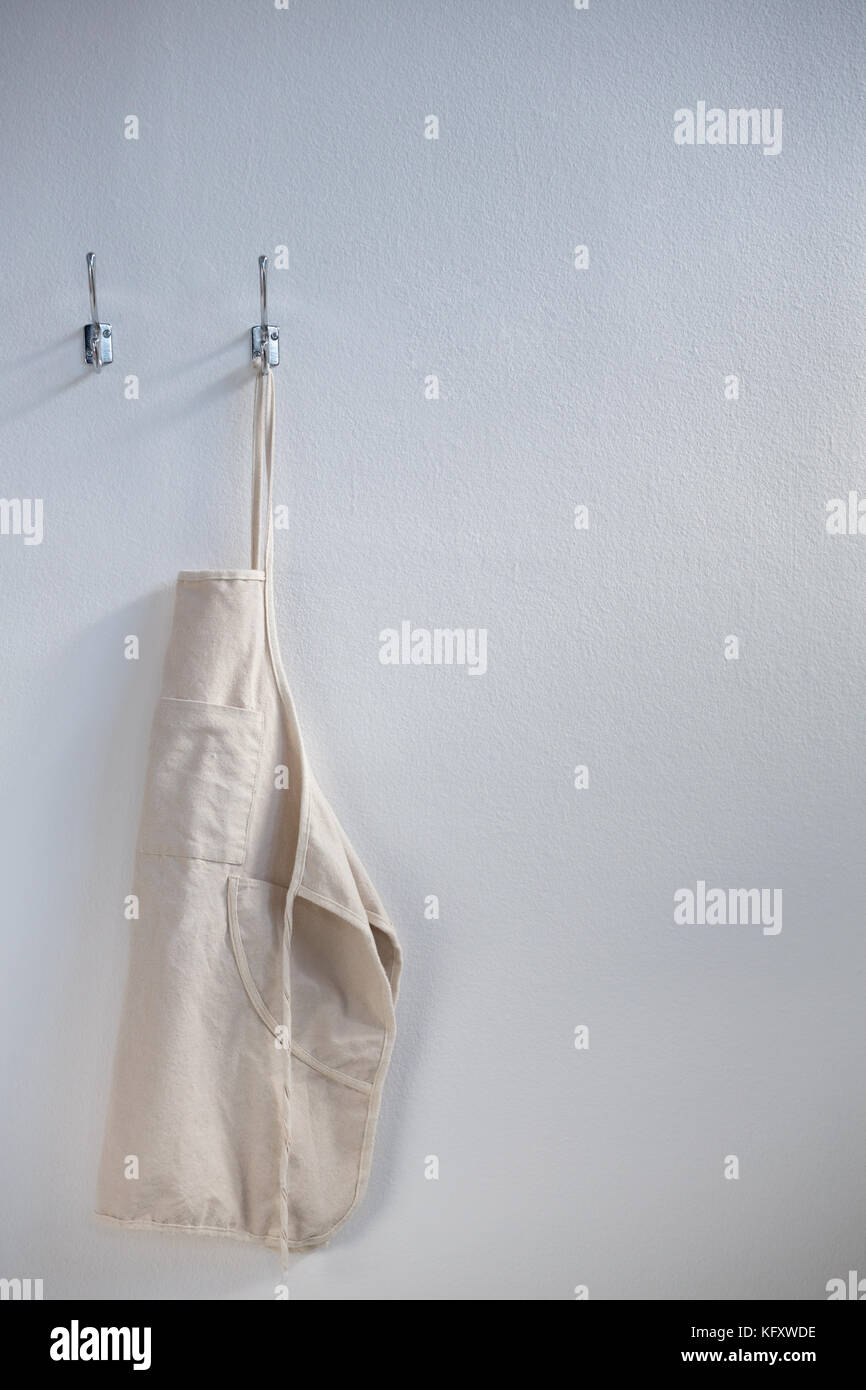 Apron hanging on hook against white wall Stock Photo - Alamy