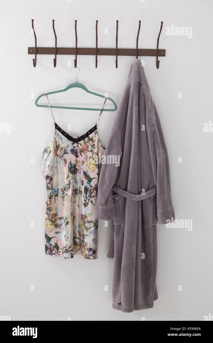 Bathrobe and nightwear hanging on hook against white wall Stock Photo ...
