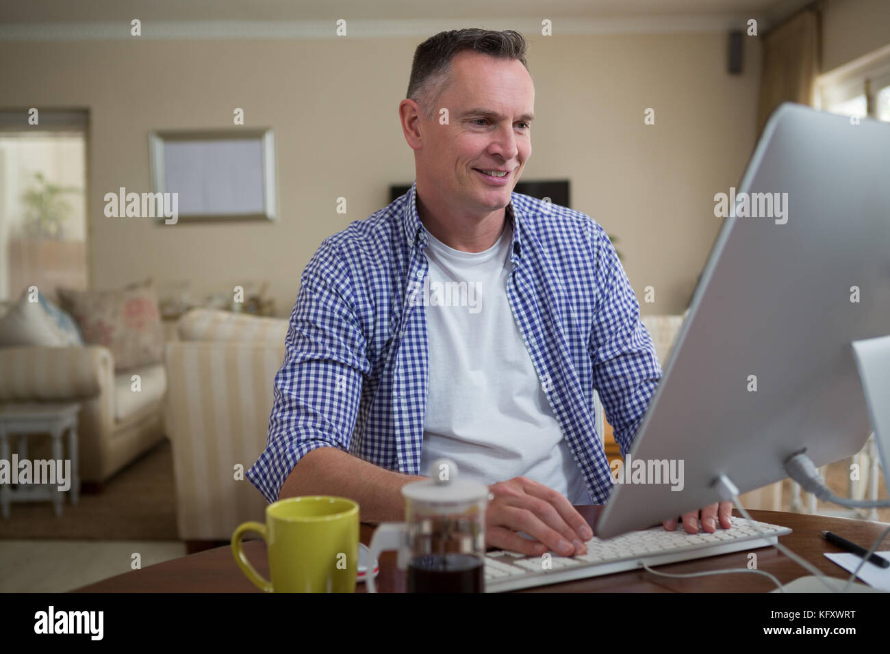 Smiling man working on computer in living room at home Stock Photo - Alamy