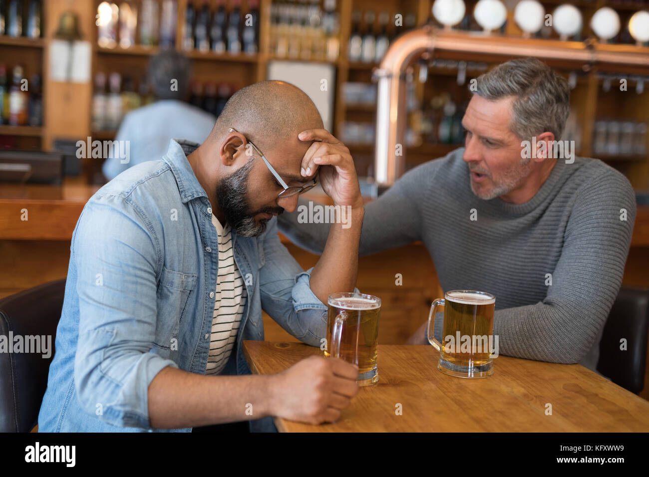 Man comforting his depressed friend in restaurant Stock Photo - Alamy