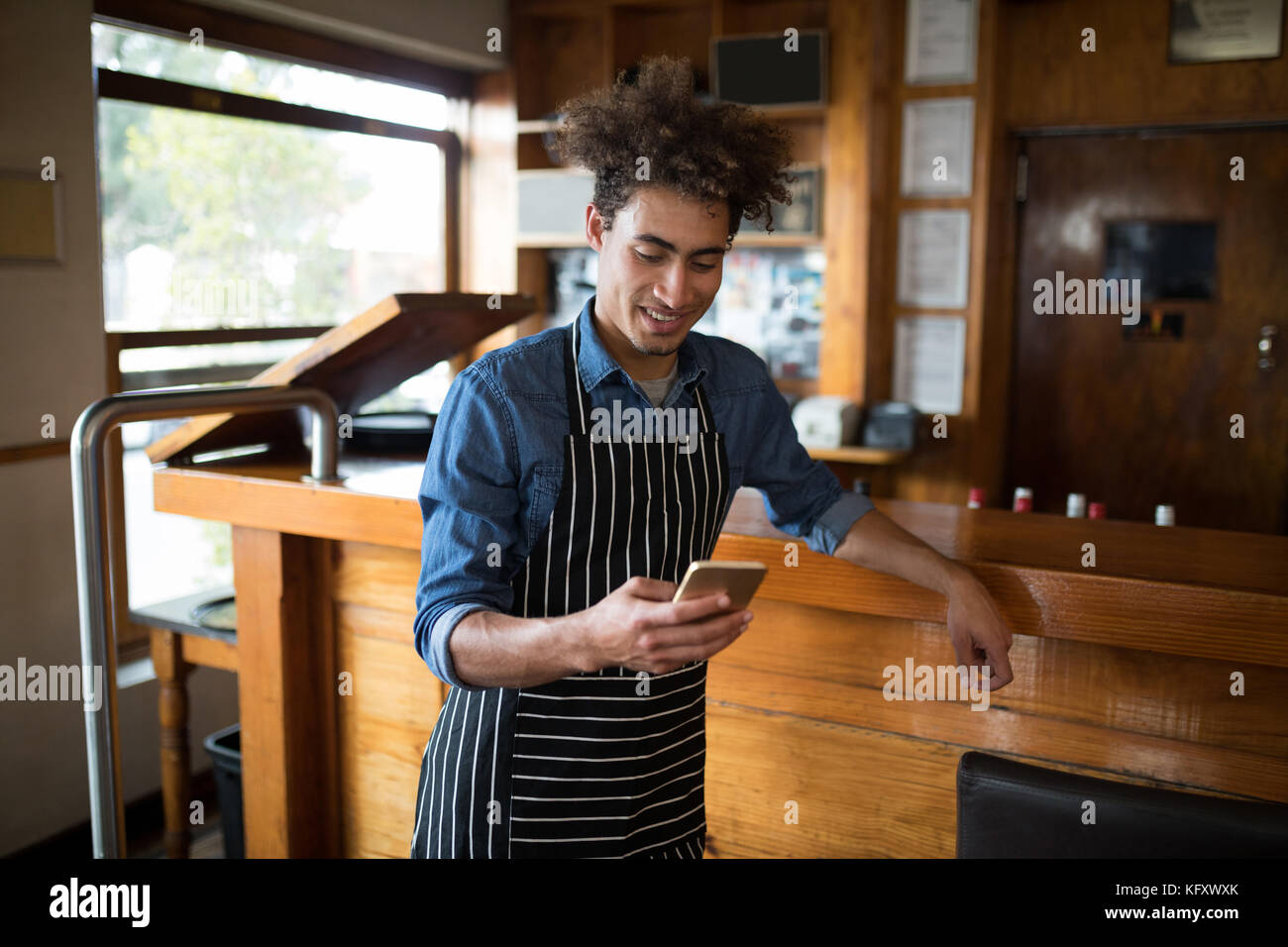 Smiling waiter using mobile phone at counter in bar Stock Photo - Alamy