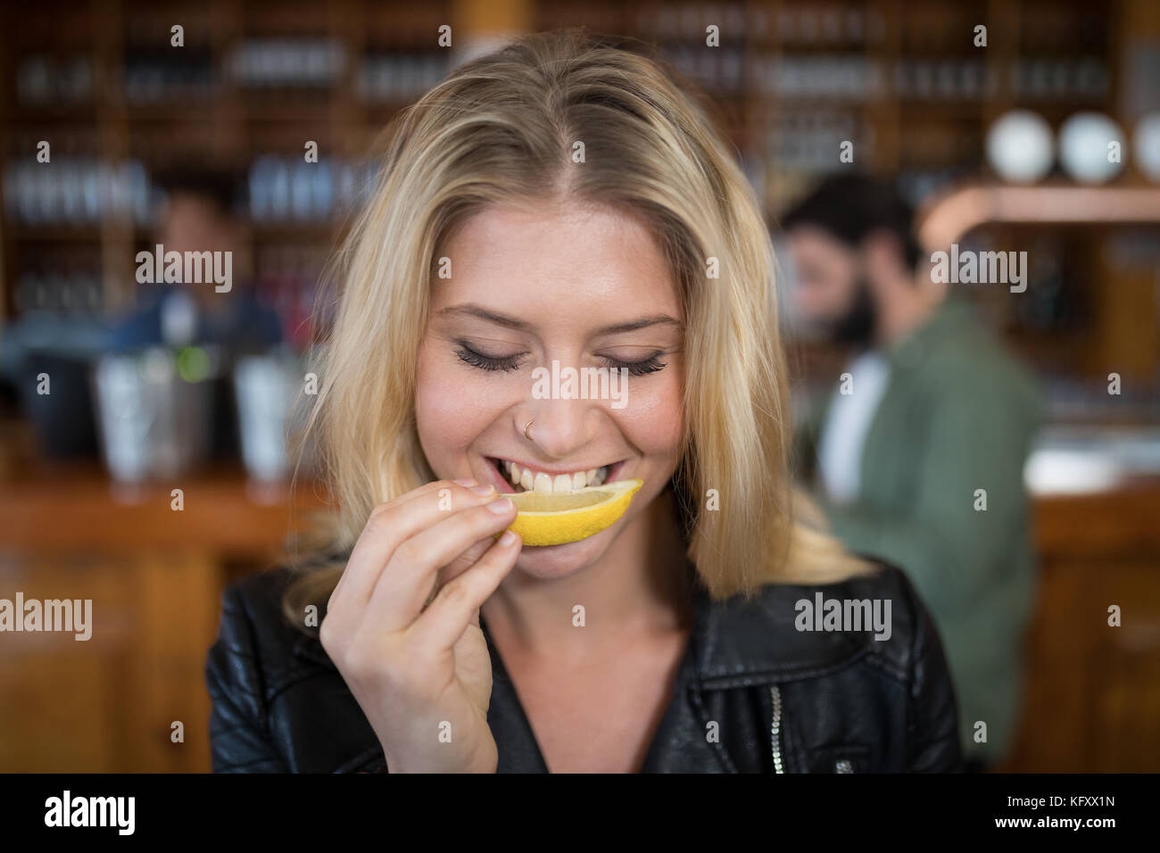 Beautiful woman biting into lemon wedge after having tequila shot in ...