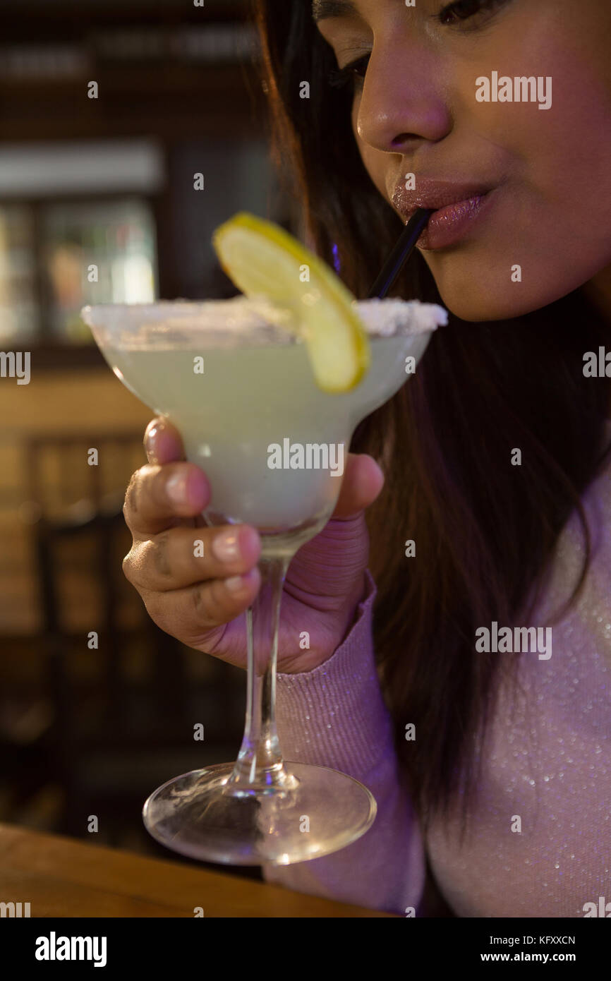 Beautiful woman sipping on a drink Stock Photo - Alamy
