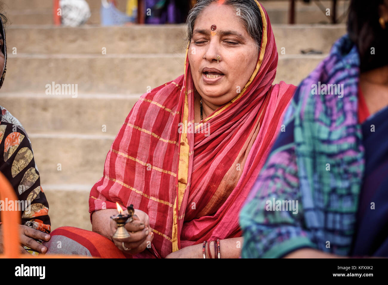 Hindu woman chanting and counting mantras for offering in the Ganges ...