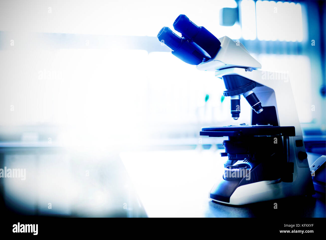 Microscope in laboratory against empty chairs in modern meeting room ...