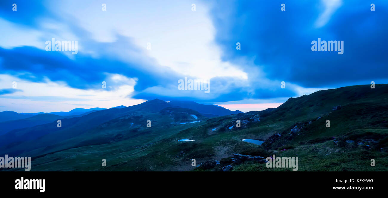 Blue hour mountain landscape with clouds and peaks after the sunset and ...