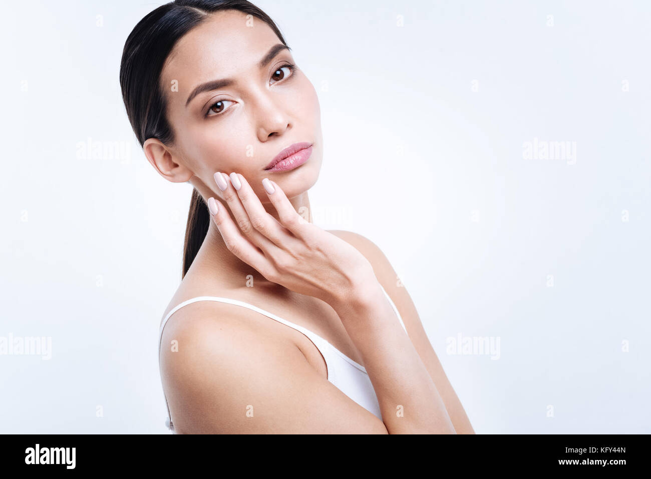 Beautiful young woman touching her cheek while posing Stock Photo - Alamy