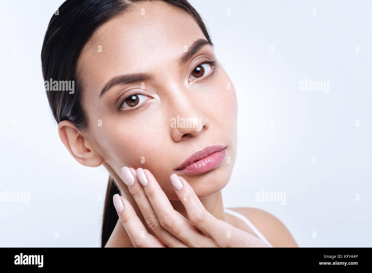 Close up of dark-haired young woman touching her cheek Stock Photo - Alamy