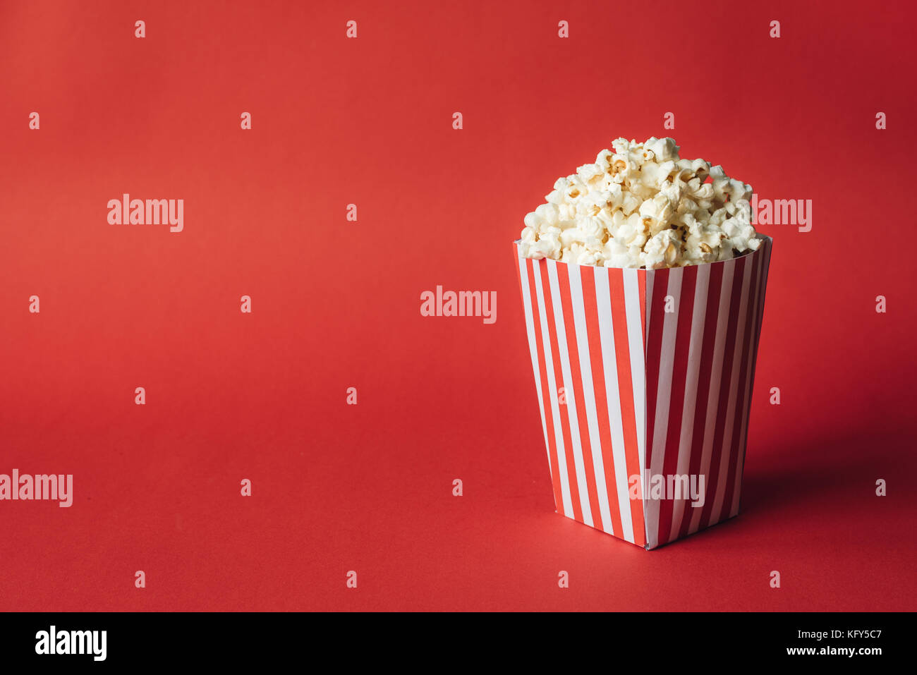 Striped box with popcorn on red background Stock Photo - Alamy