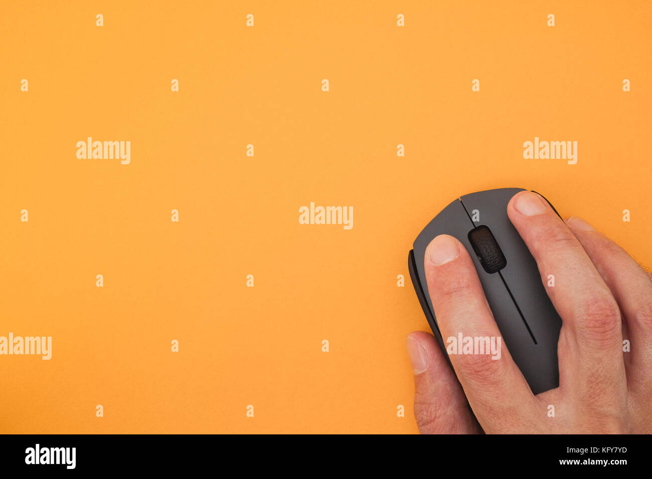 Person using wireless computer mouse on yellow background. Close up ...