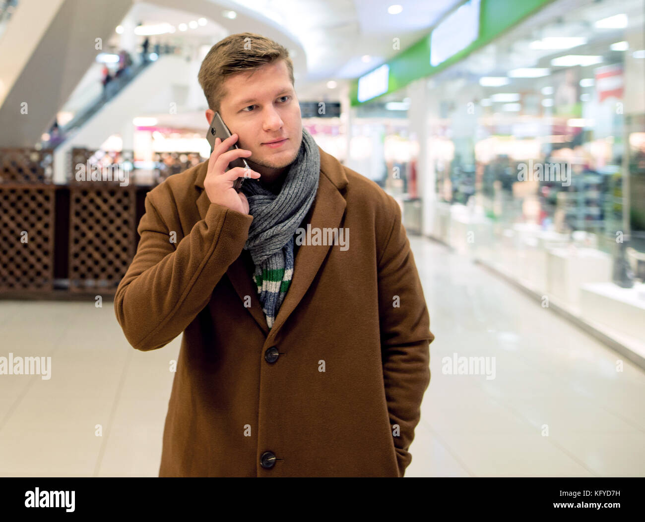 man in the coat with the phone in the store Stock Photo - Alamy