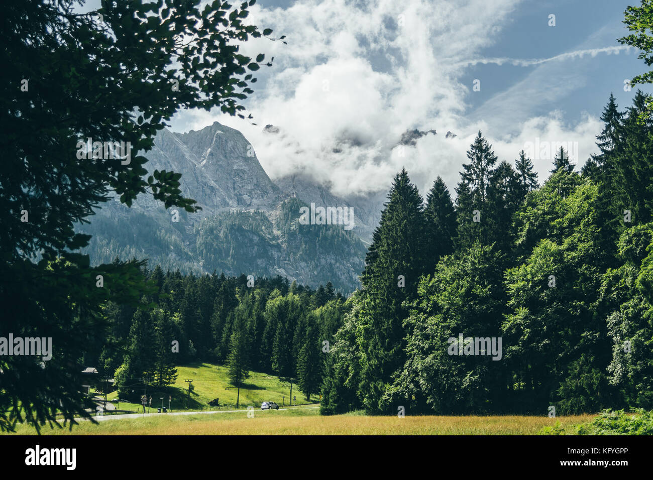 Zugspitze mountain covered in clouds on a summer day with blue skies ...