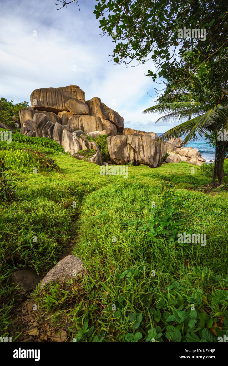 Hiking a footpath in the wilderness to mighty red granite rocks in lush ...