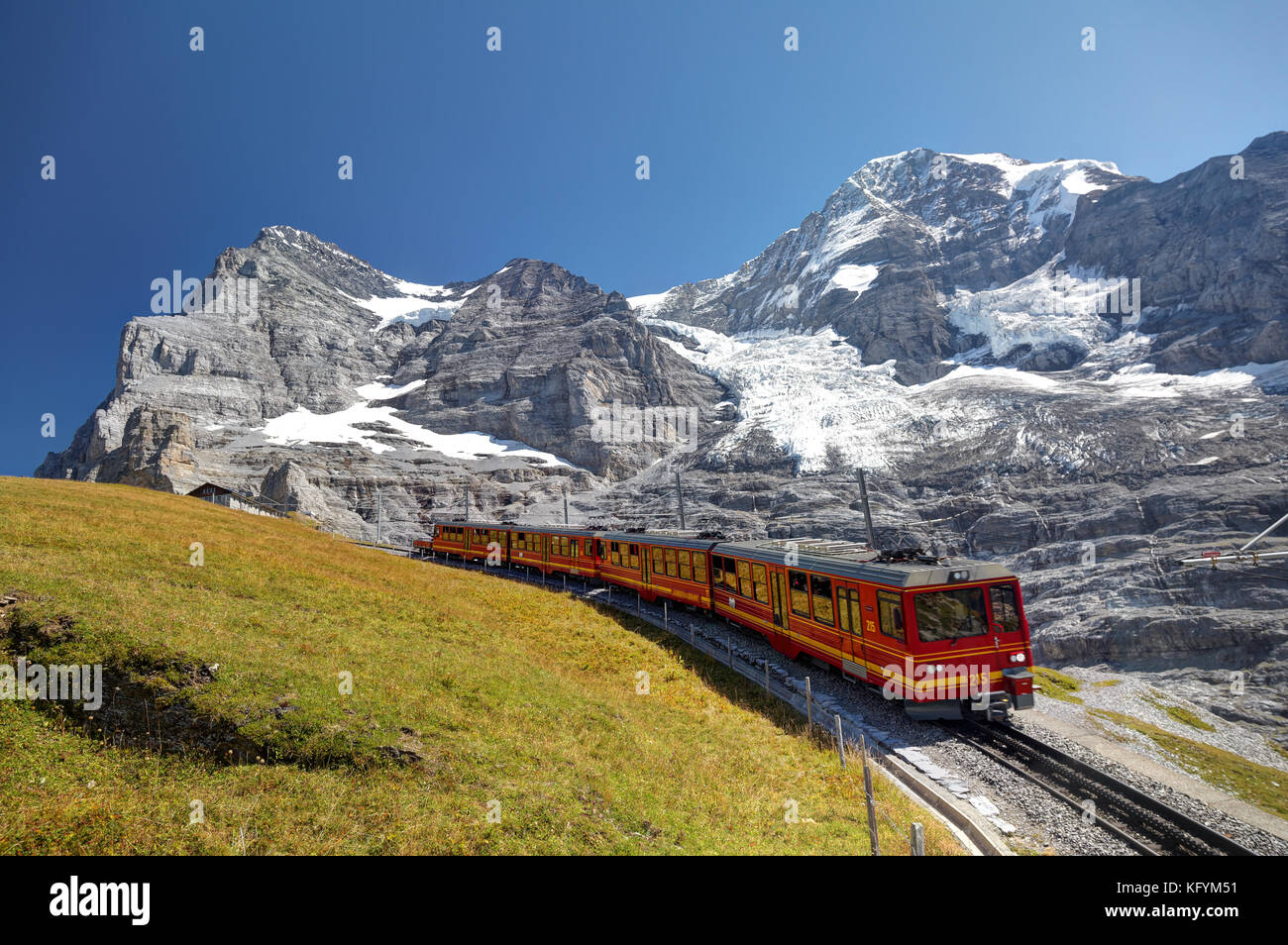 Red rail cars on the Jungfrau railway run below the north face of the ...